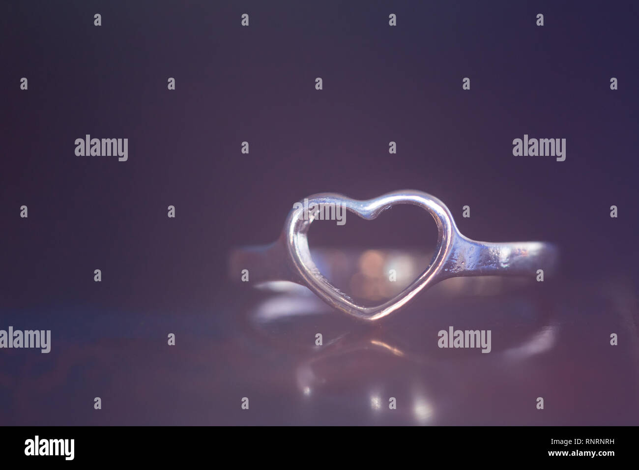 Silver heart shape ring with purple background Stock Photo - Alamy