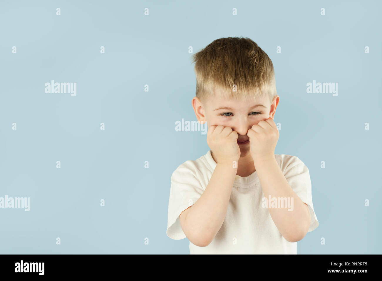 Portrait of an emotional handsome boy on an isolated blue background ...