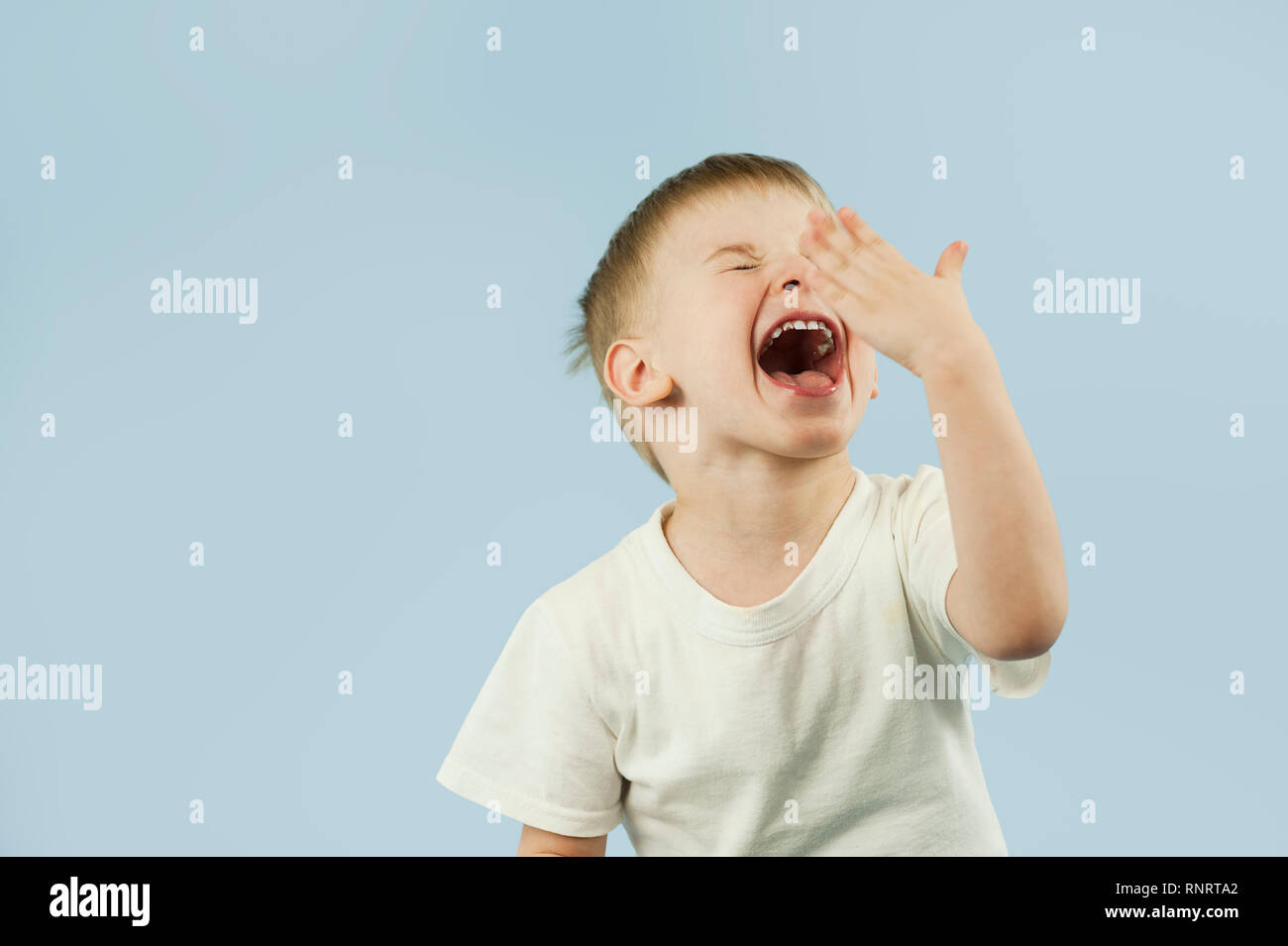Portrait of an emotional handsome boy on an isolated blue background ...