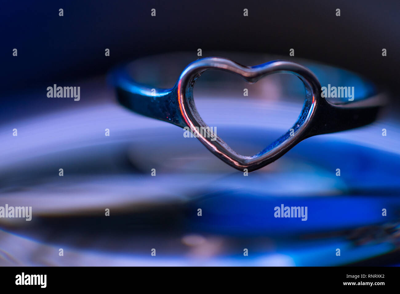 Silver heart shape ring with blue background Stock Photo - Alamy