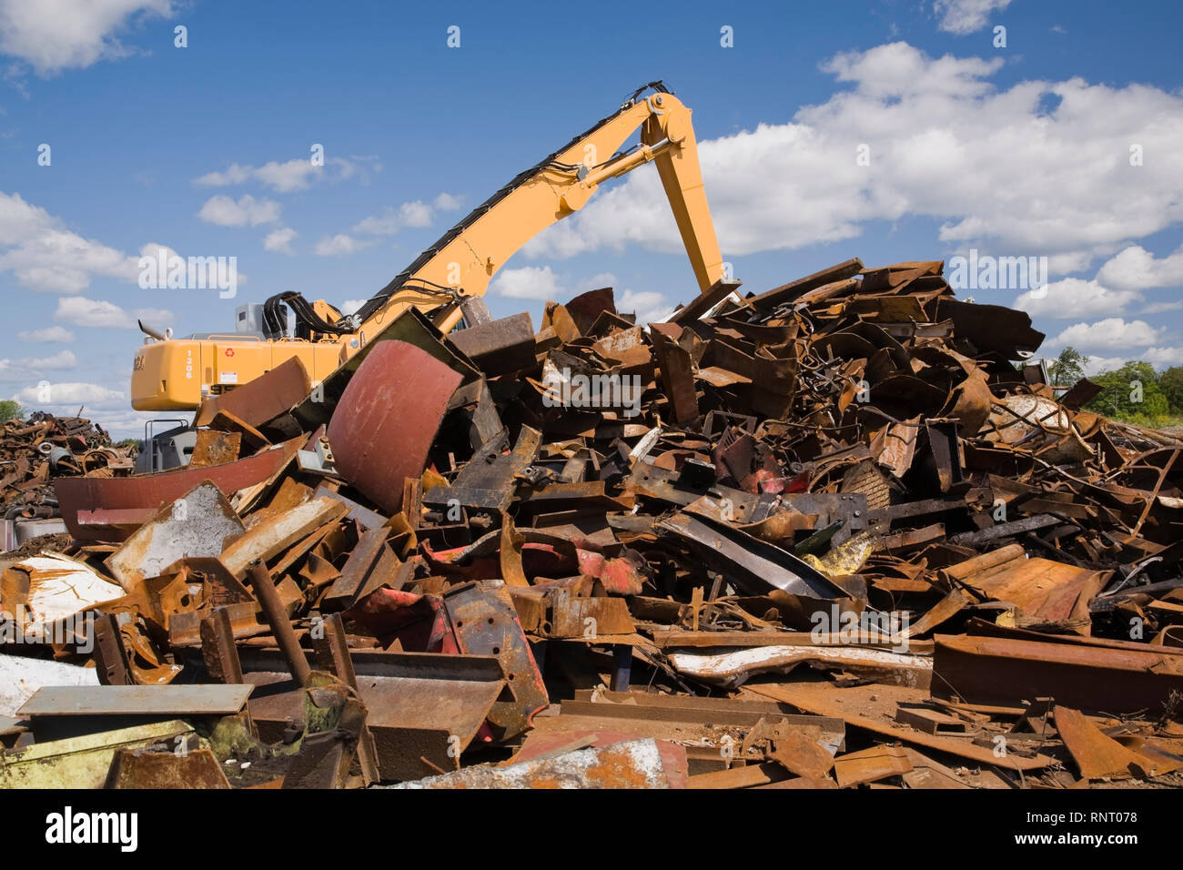 Crane loader with grappling arm and assorted rusted ferrous metal parts ...