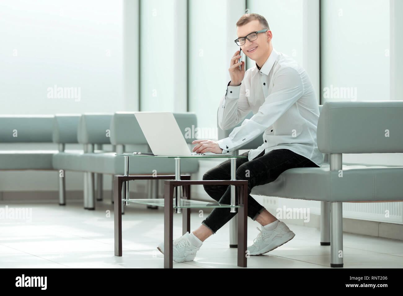 smiling employee sitting at his Desk in the office hall Stock Photo - Alamy