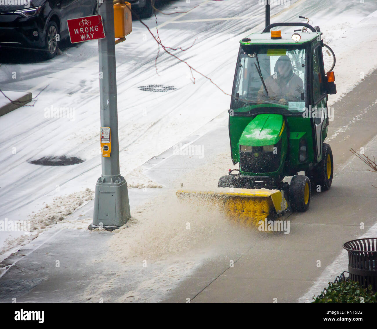 A tractor equipped with a broom sweeps up the snow in the Chelsea ...