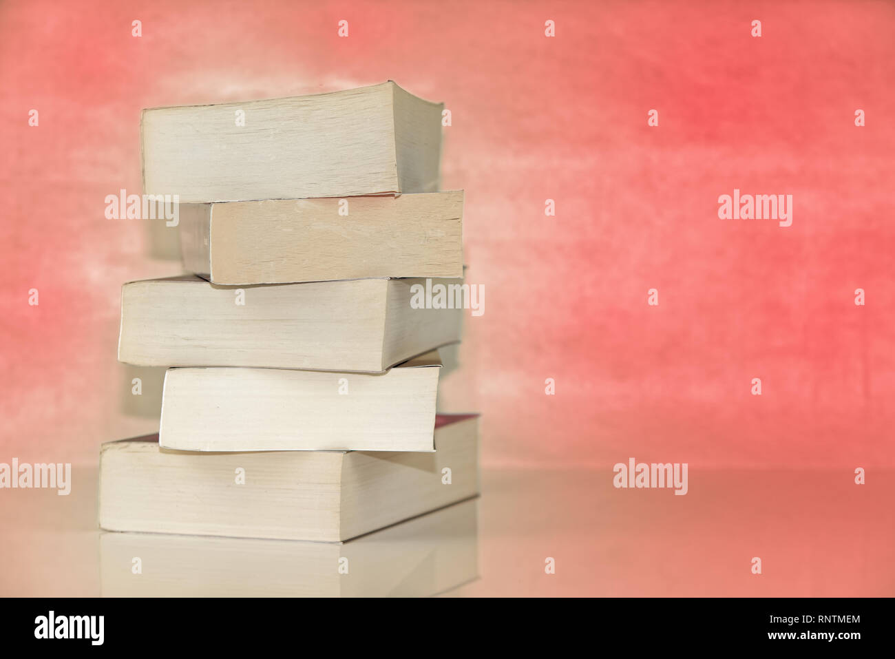 Pile of old paper books against red background Stock Photo - Alamy