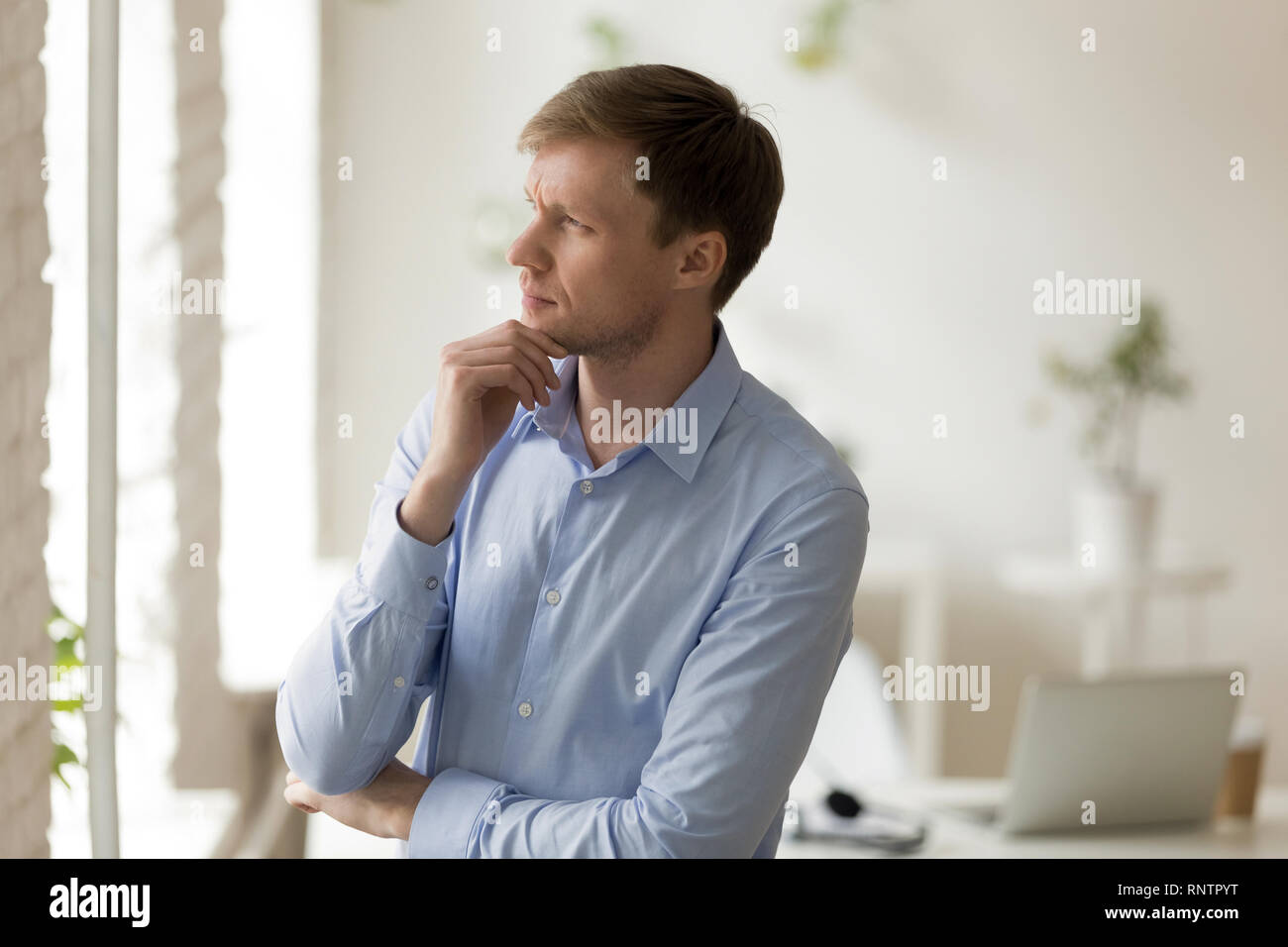 Serious businessman standing in office room thinking making a decision ...