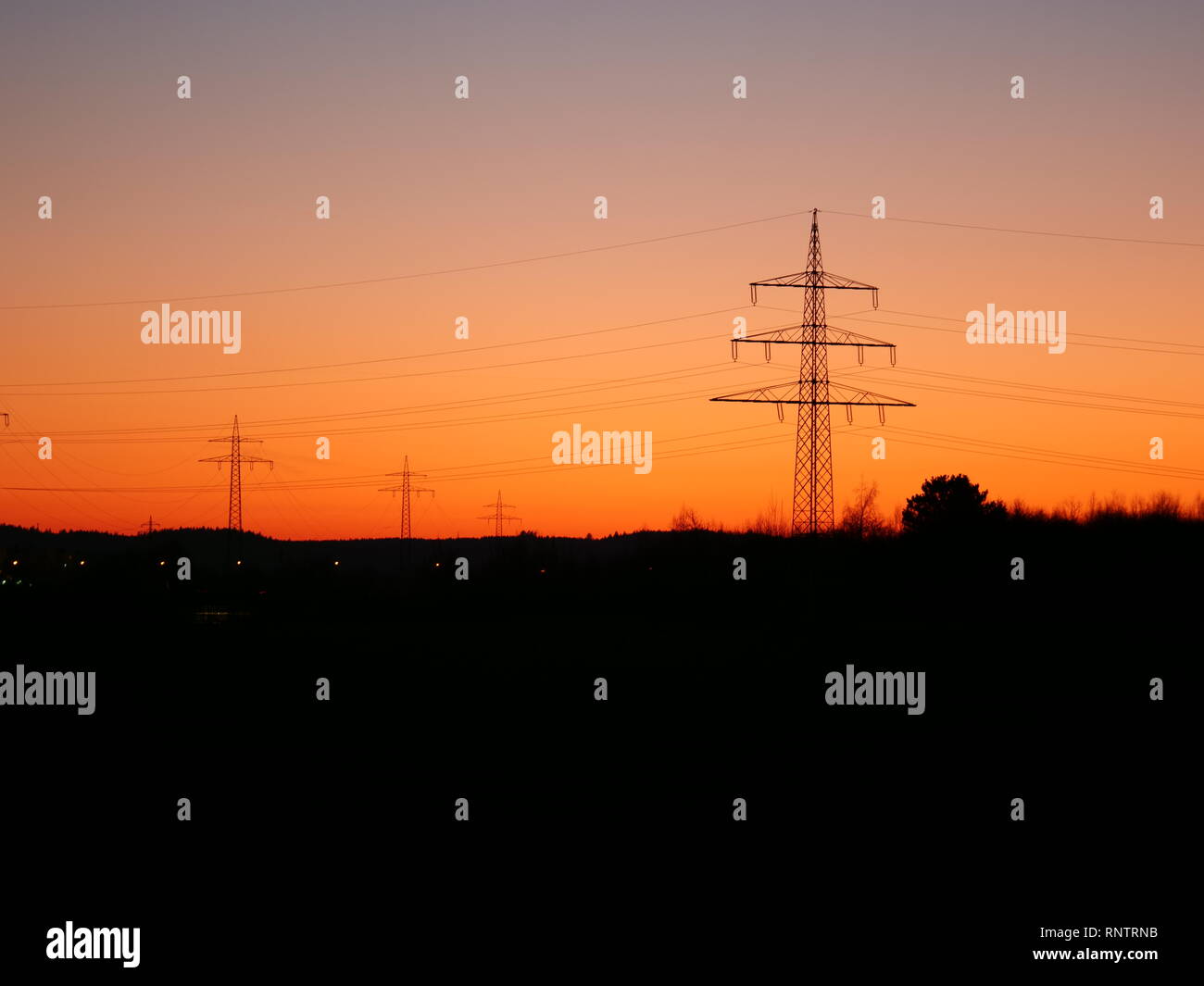 Image of silhouettes of power pylons in the landscape during colorful ...