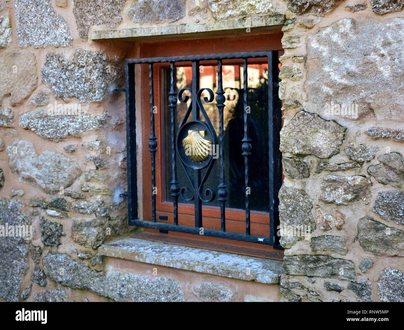 Window with iron grill and golden scallop shell, symbol of Camino de ...