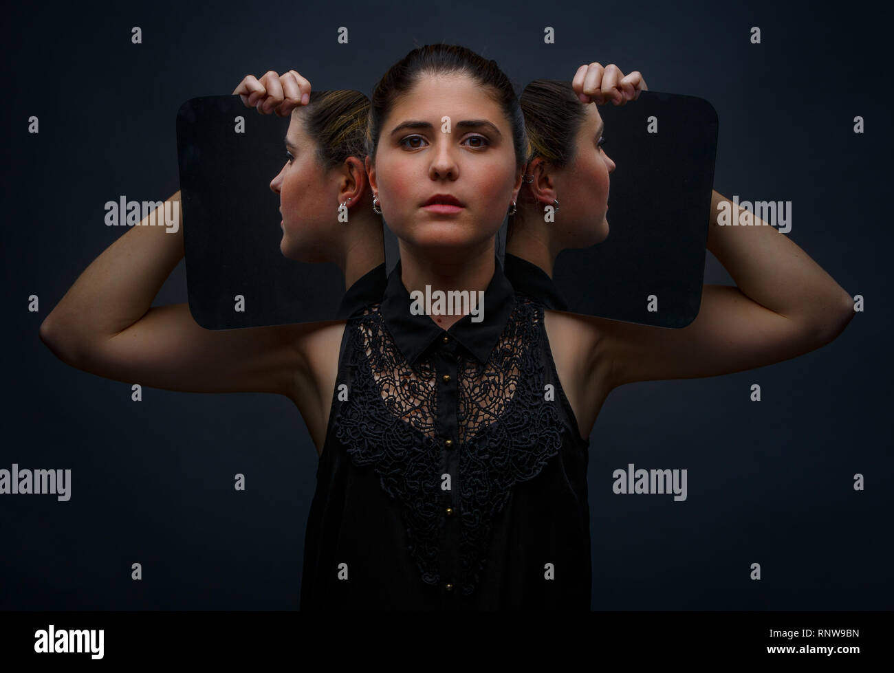 Modern model holding mirrors on sides of face Stock Photo - Alamy