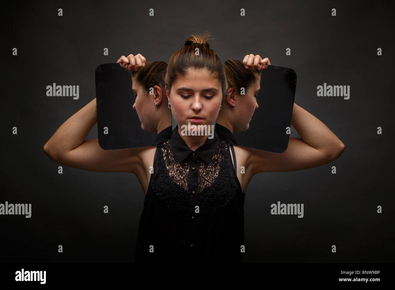 Modern model holding mirrors on sides of face Stock Photo - Alamy