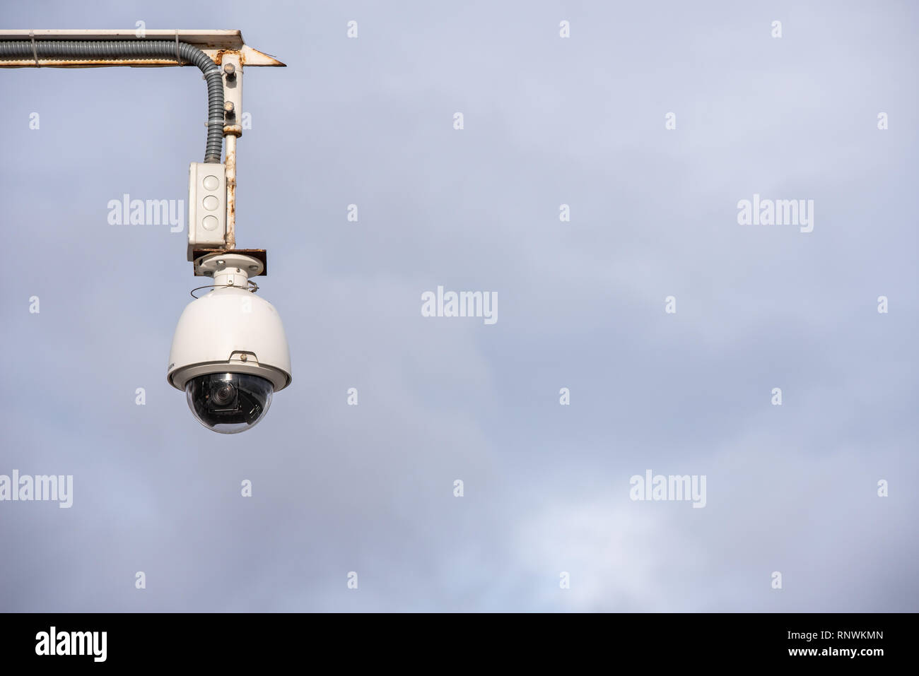 Security camera hung to monitor people in a city, isolated over blue ...