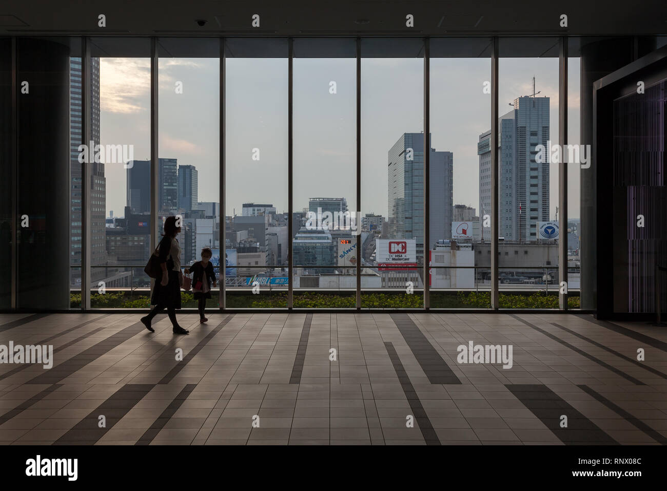 A woman and child walk in front of large view windows in the Hikarie ...