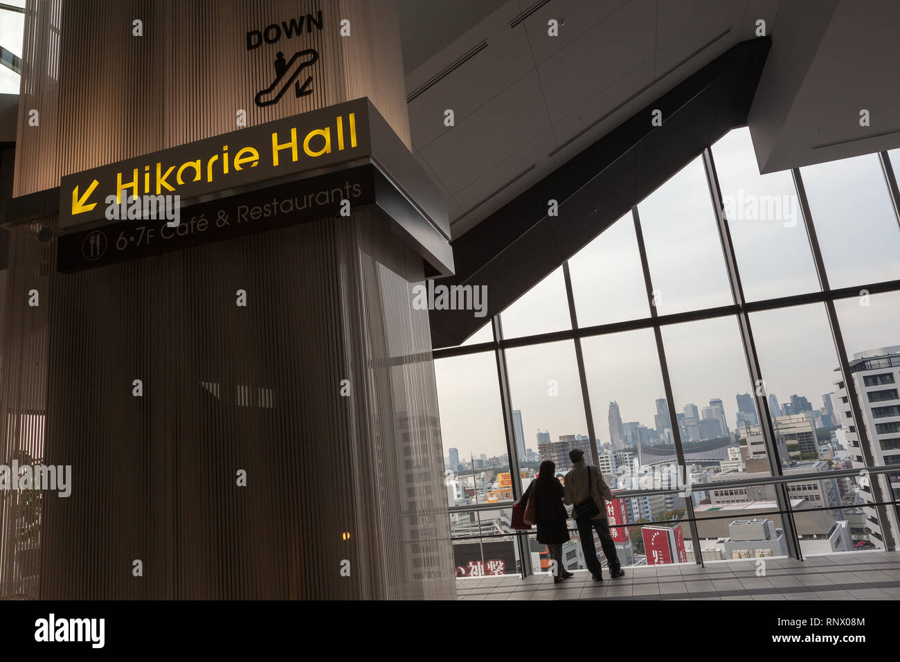 A Japanese woman and man look out a view of Shinjuku from large view ...