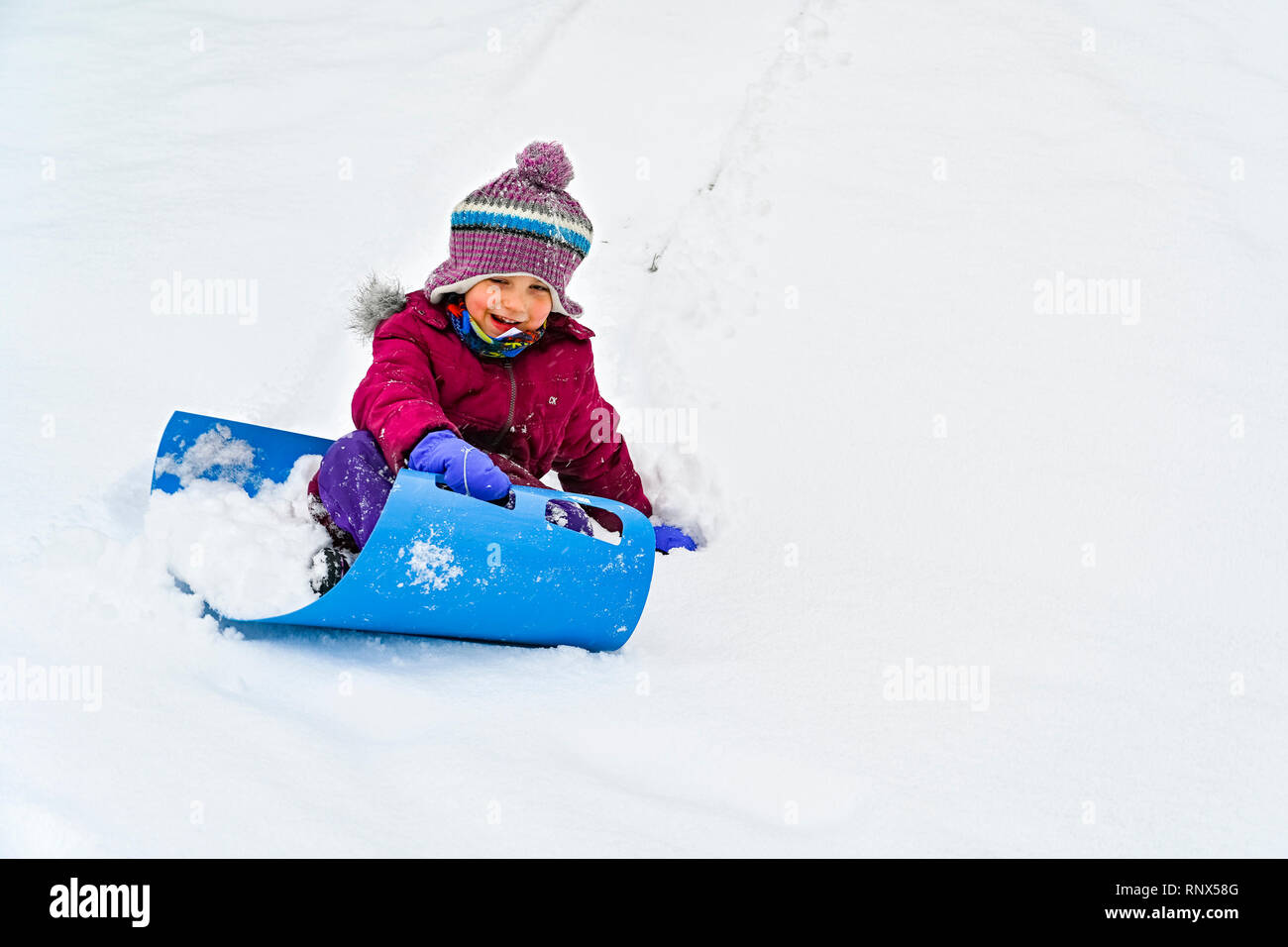 Young girl snow sledding down hill Stock Photo - Alamy