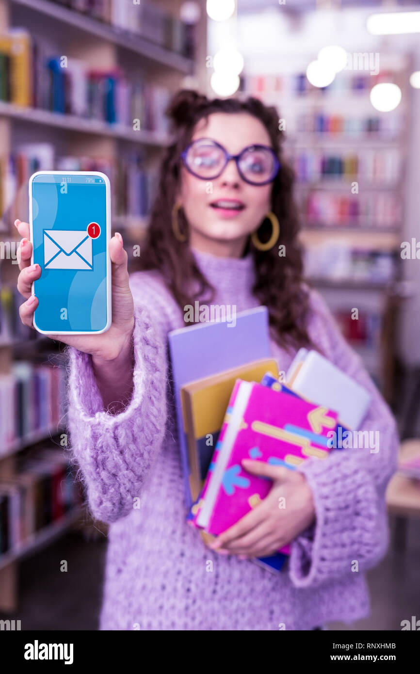 Curly good-looking young woman displaying unread message Stock Photo ...