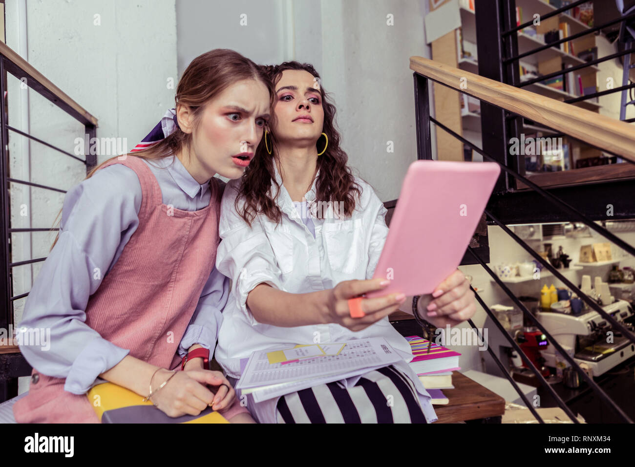 Terrified and scared girls being confused with information on tablet ...