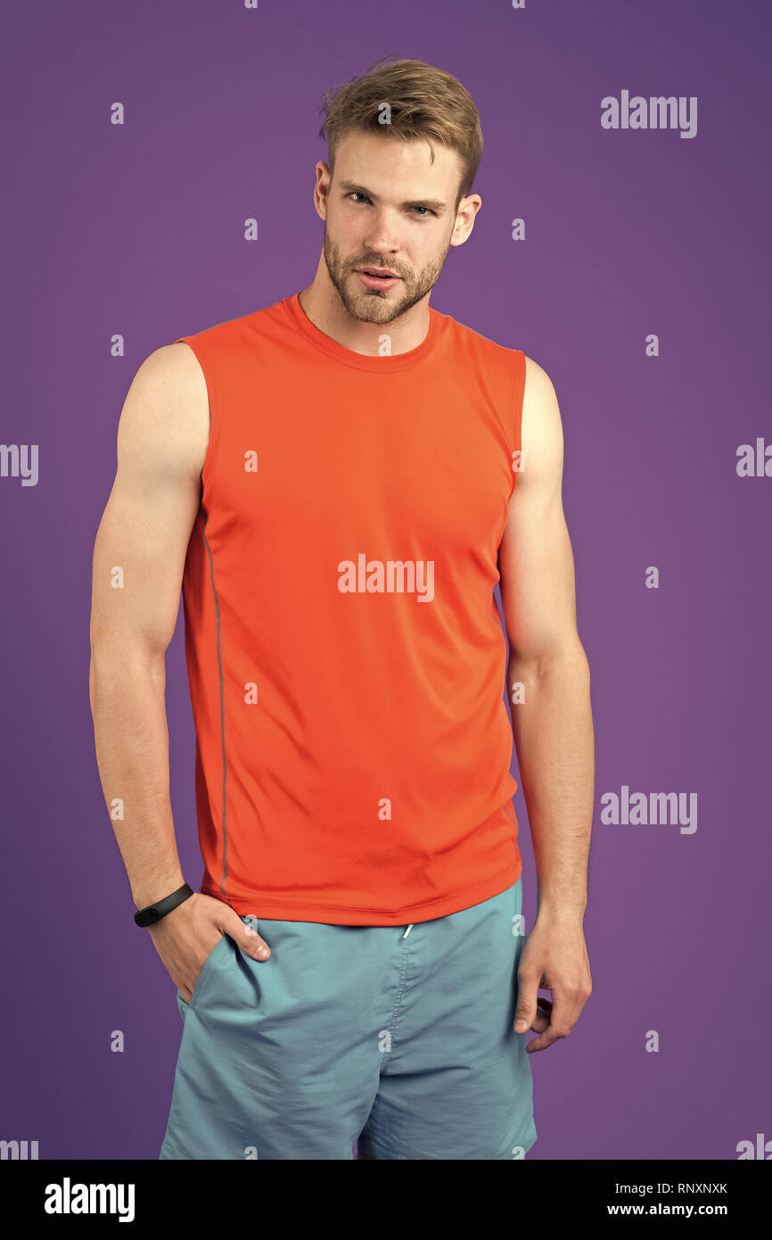 Athlete on violet background. Muscular man in orange vest and blue ...