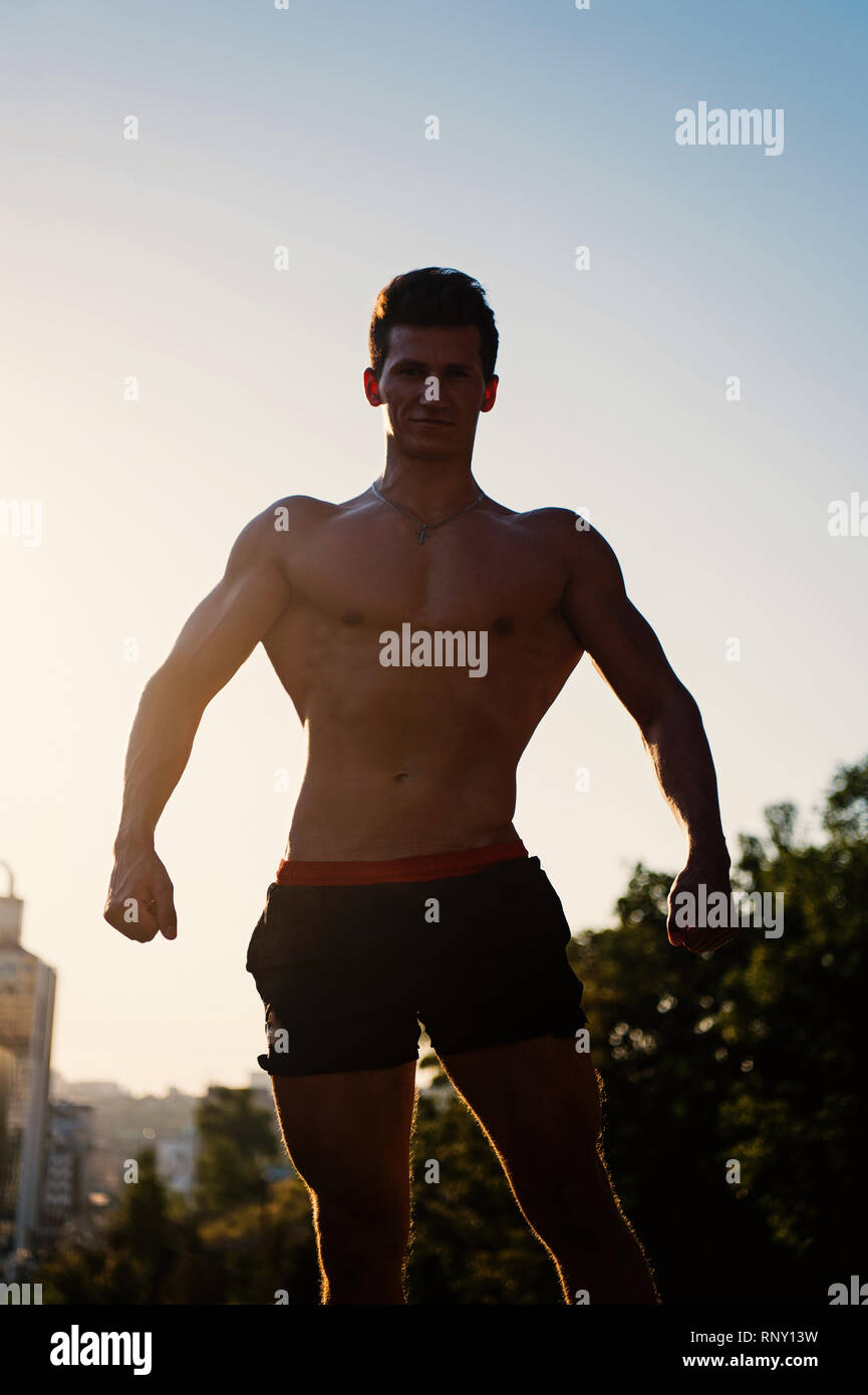 Bodybuilder showing muscular body, muscles, biceps, triceps on sunset ...