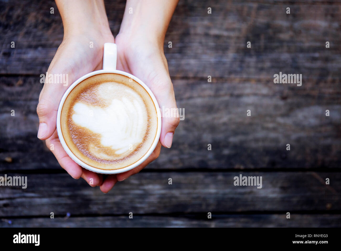 Hands holding coffee cup with wooden table background Stock Photo - Alamy