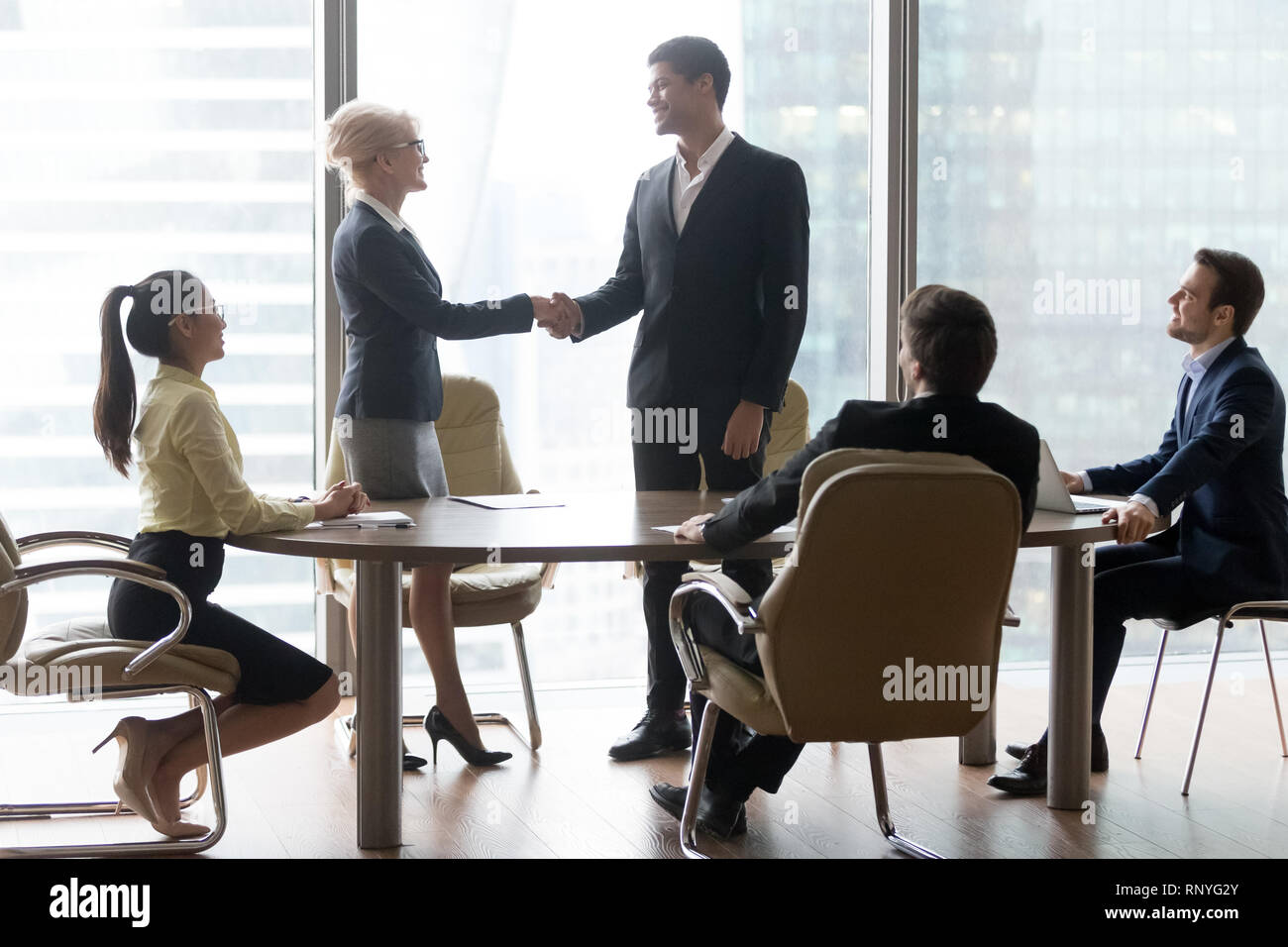Happy middle-aged boss handshaking welcoming new partner at team ...