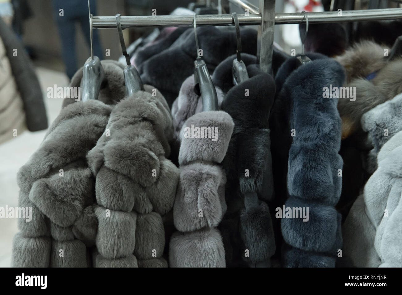 Row of gray fur coats on the rack, winter season collection in clothing ...