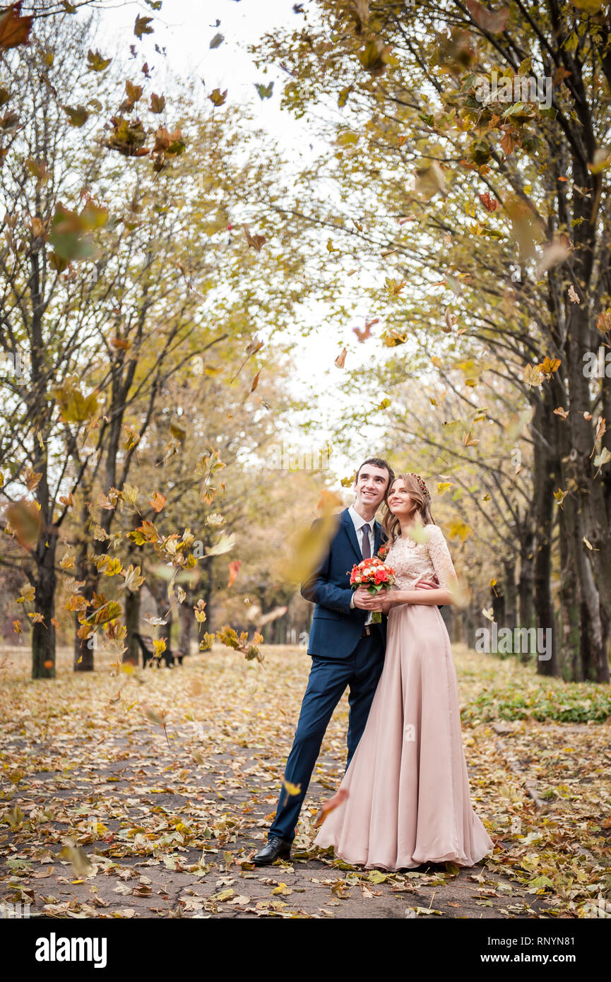 Smilng newlyweds hug under a fall of autumn leaves Stock Photo - Alamy