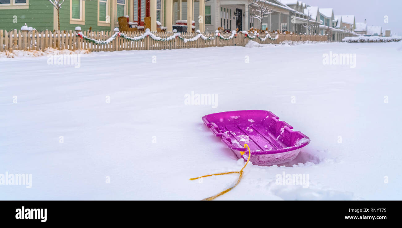 Puprle sled on snow with homes in the background Stock Photo - Alamy