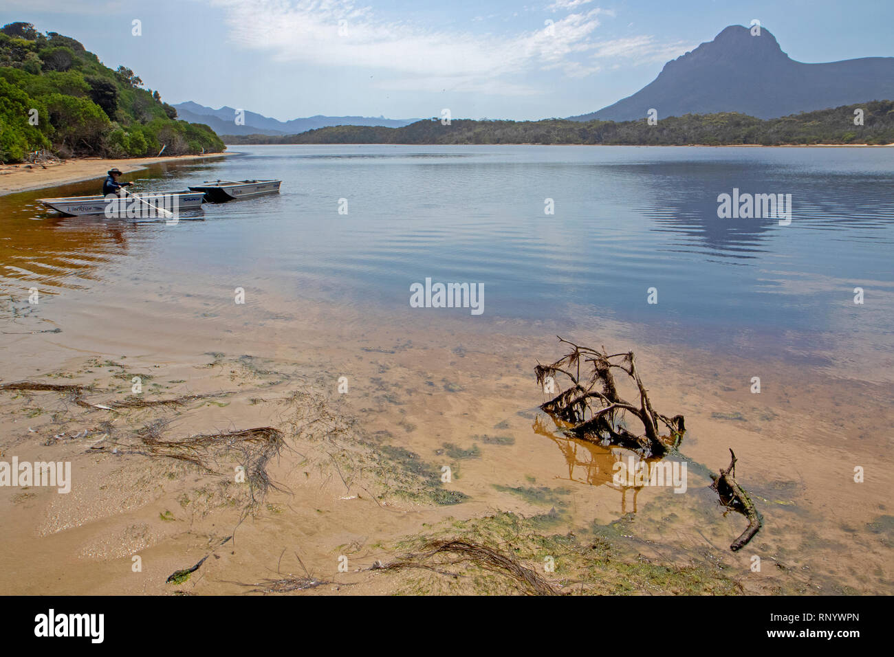 Hiker rowing boats across New River Lagoon on the South Coast Track ...