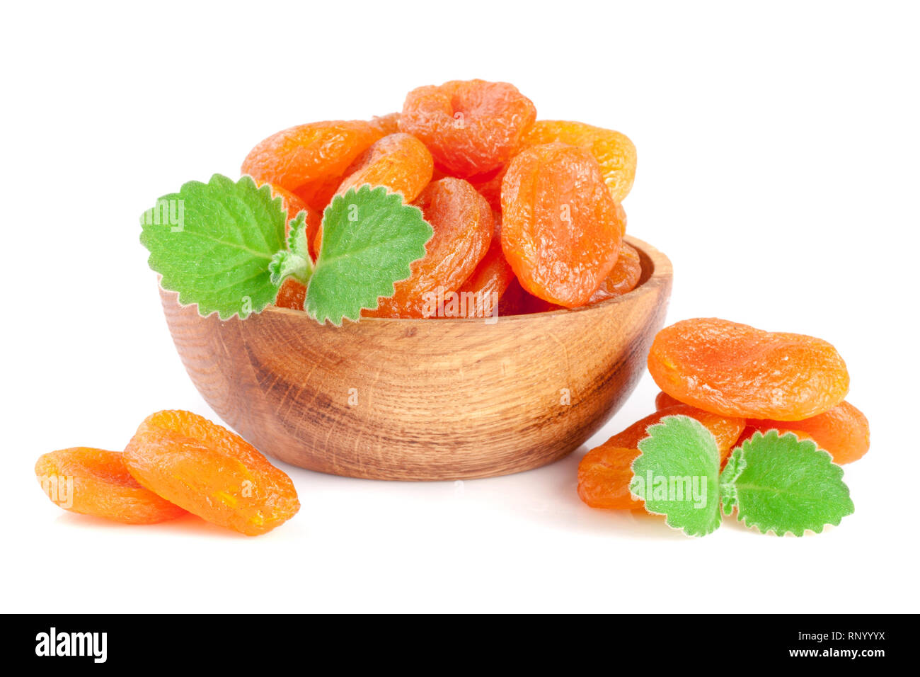 Dried apricots in a wooden bowl with mint leaves isolated on white ...