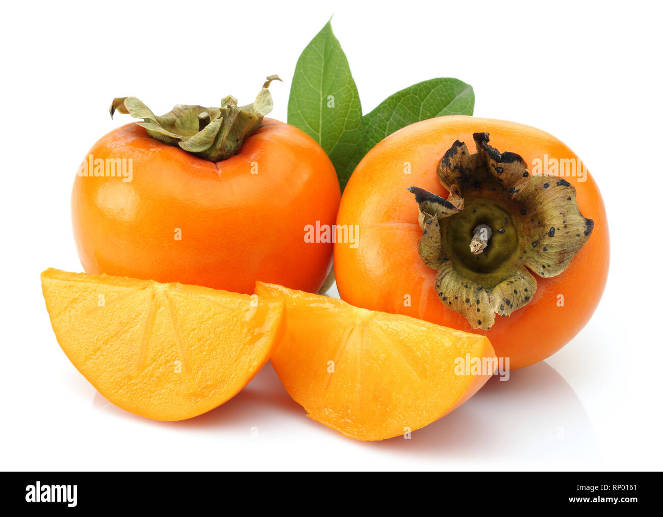 Slice and whole Persimmon with green leaves isolated on white ...