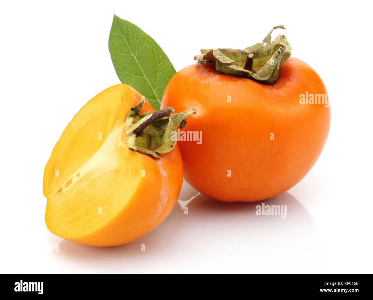 Half and whole Persimmon with green leaf isolated on white background ...