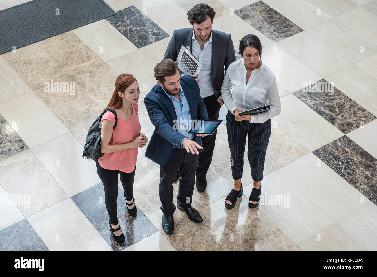 Businessman pointing while talking with his colleagues in hotel lobby ...
