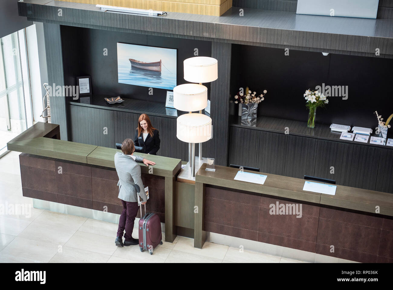 Female receptionist talking with businessman while standing at counter ...