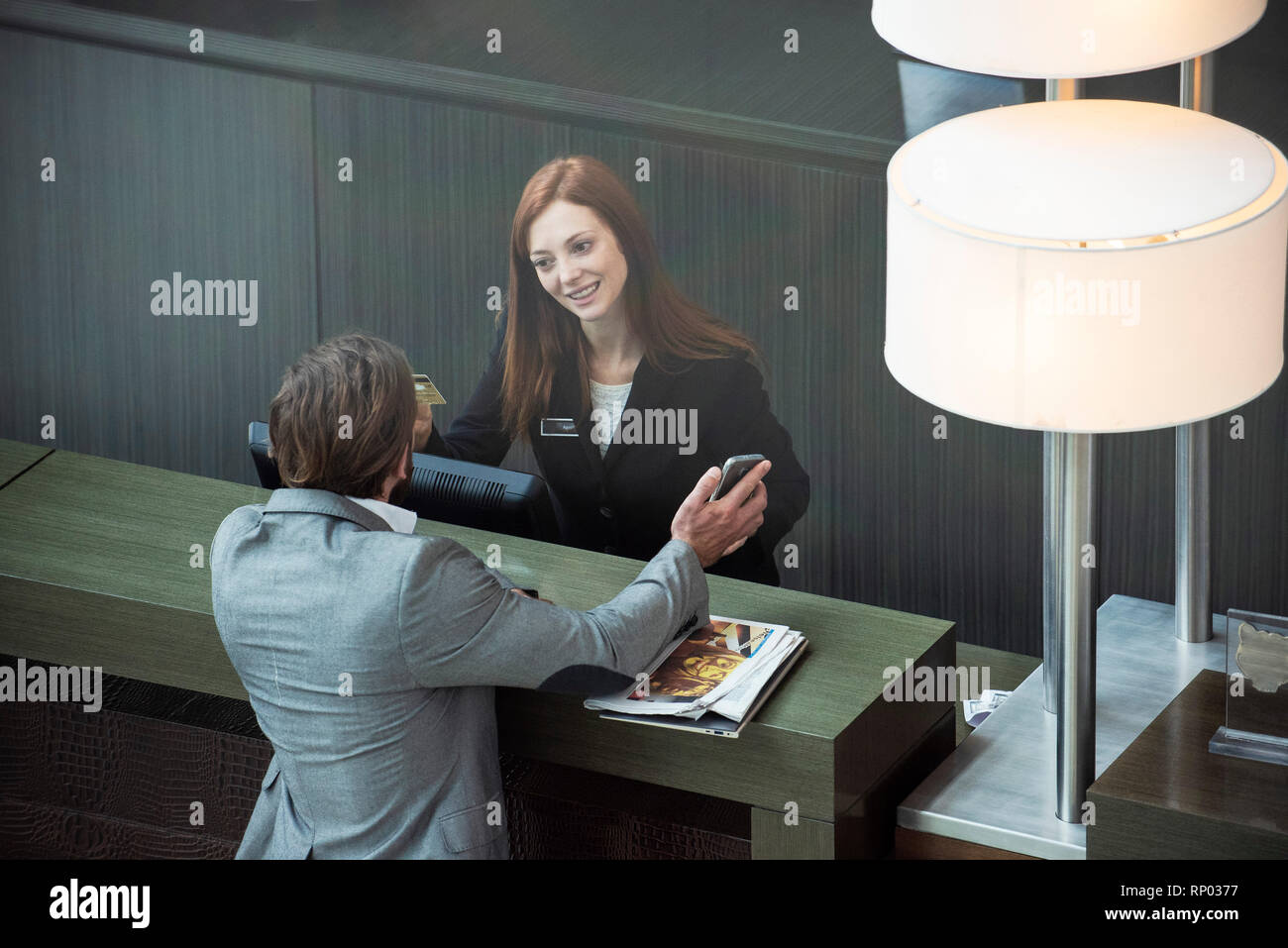 Businessman showing smart phone to female receptionist Stock Photo - Alamy