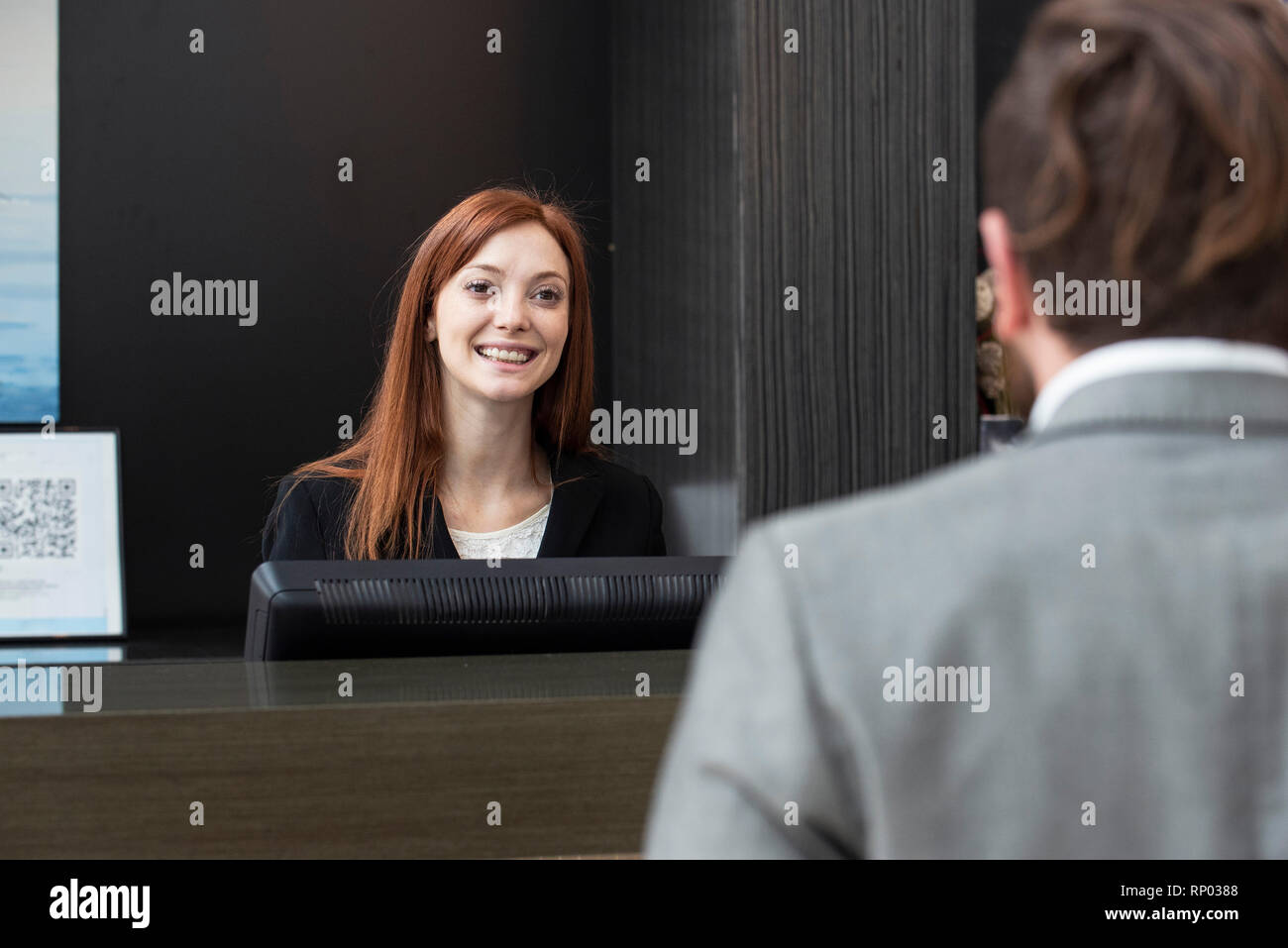 Female receptionist looking at businessman Stock Photo - Alamy