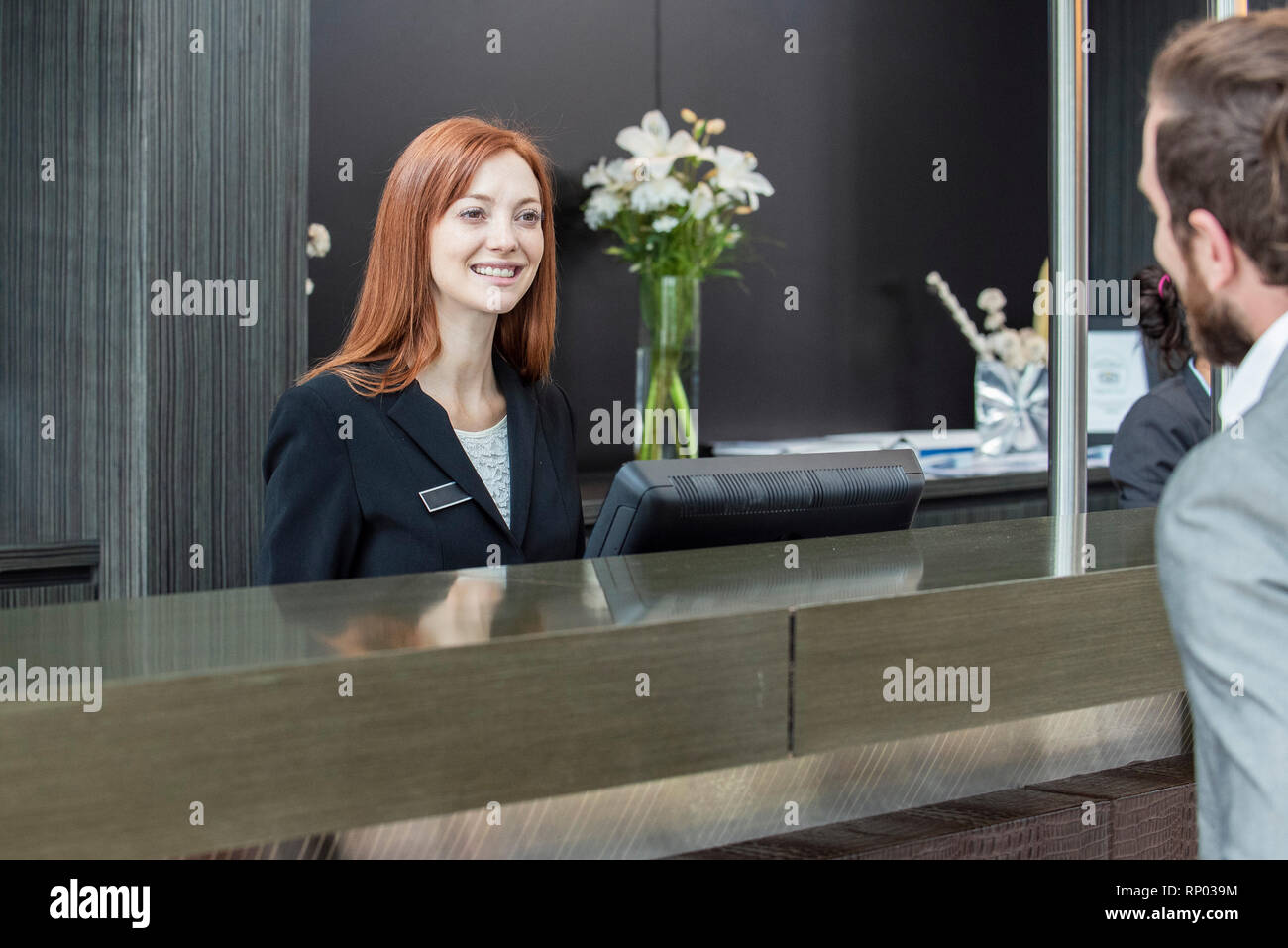 Female receptionist looking at businessman Stock Photo - Alamy