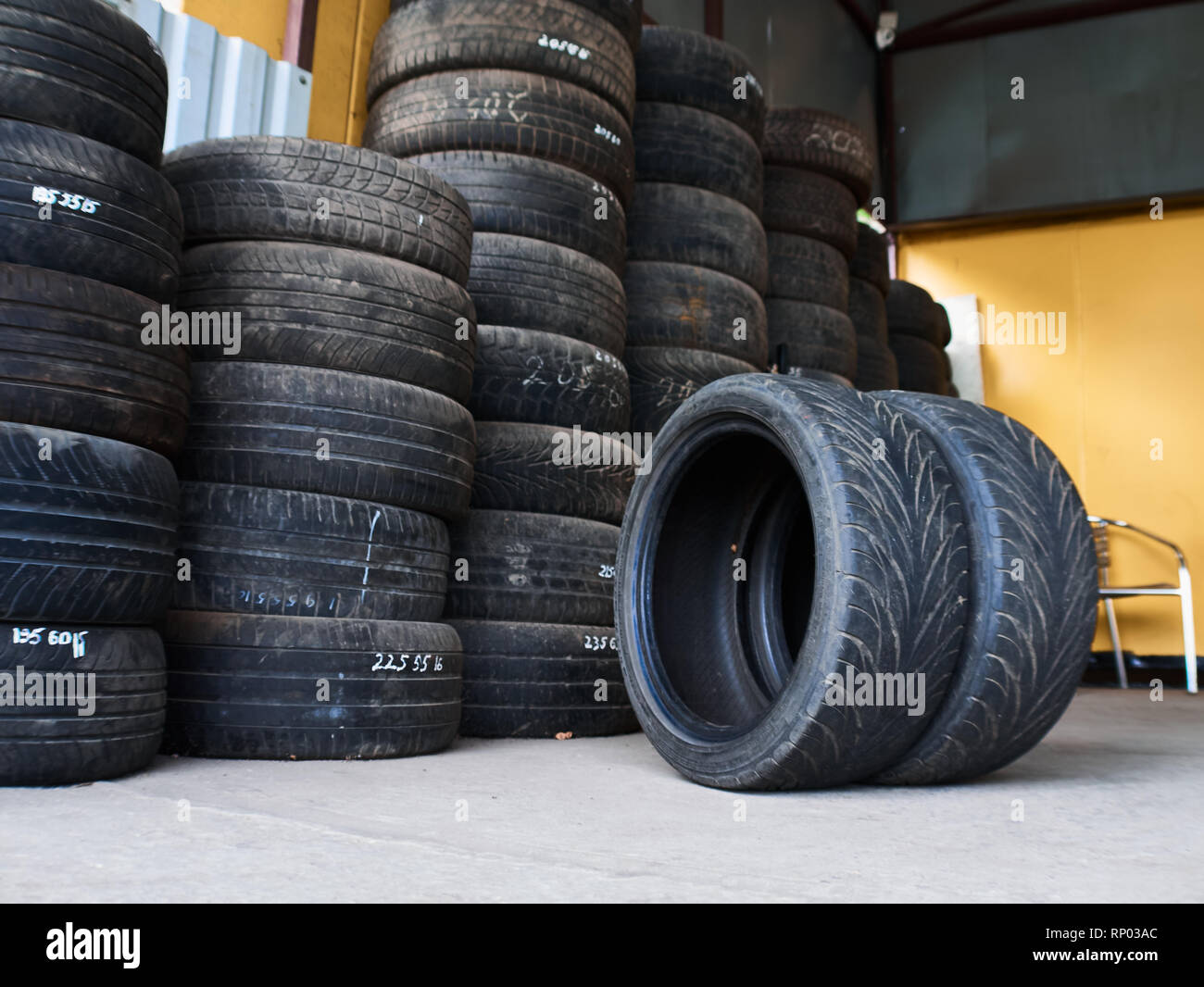 Used car tires stacked in piles at junkyard. Old wheels recycling and utilization concept. Tire ...