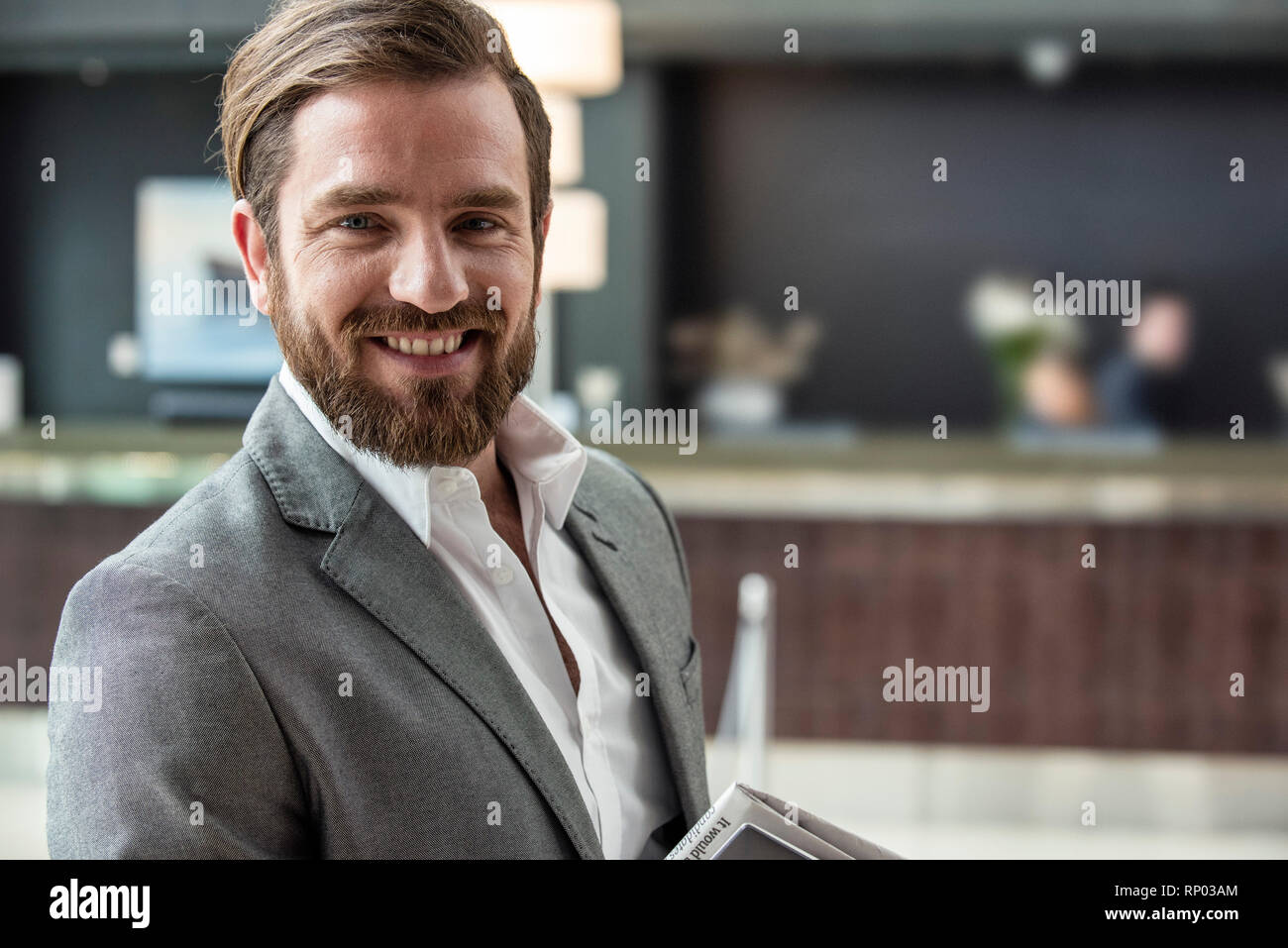 Smiling businessman standing in hotel lobby Stock Photo - Alamy