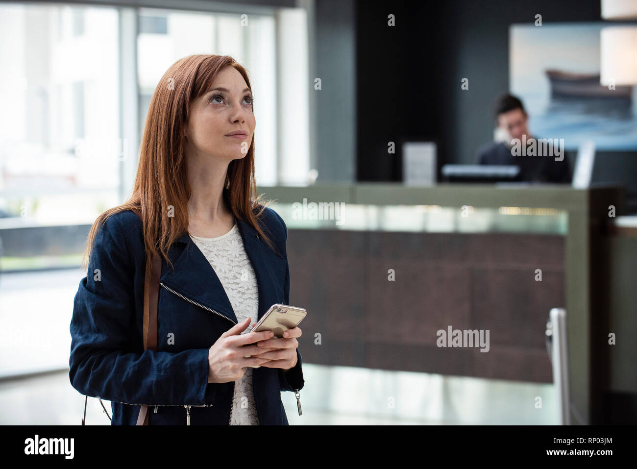 Woman standing in hotel lobby Stock Photo - Alamy