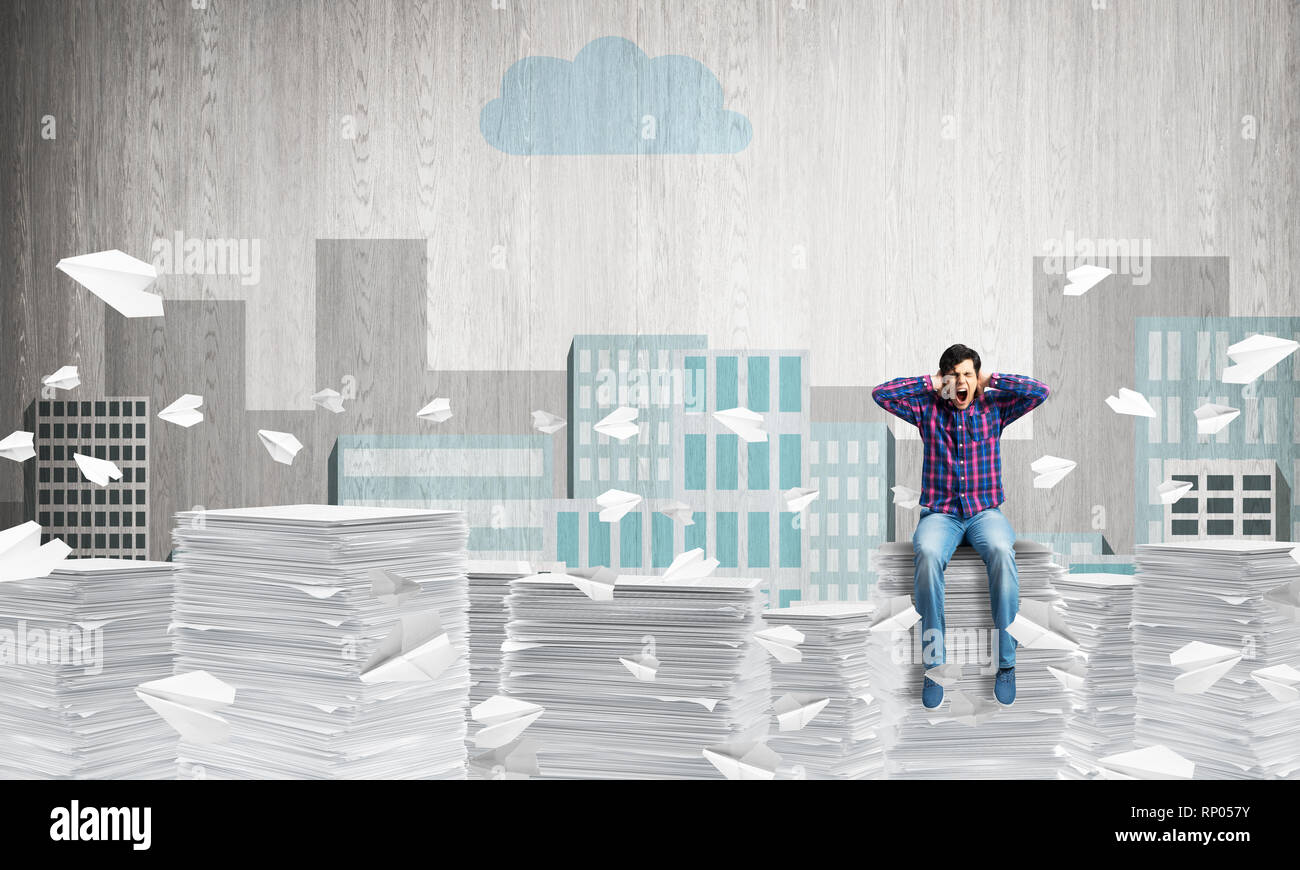 Young man sitting on pile of paper documents Stock Photo - Alamy