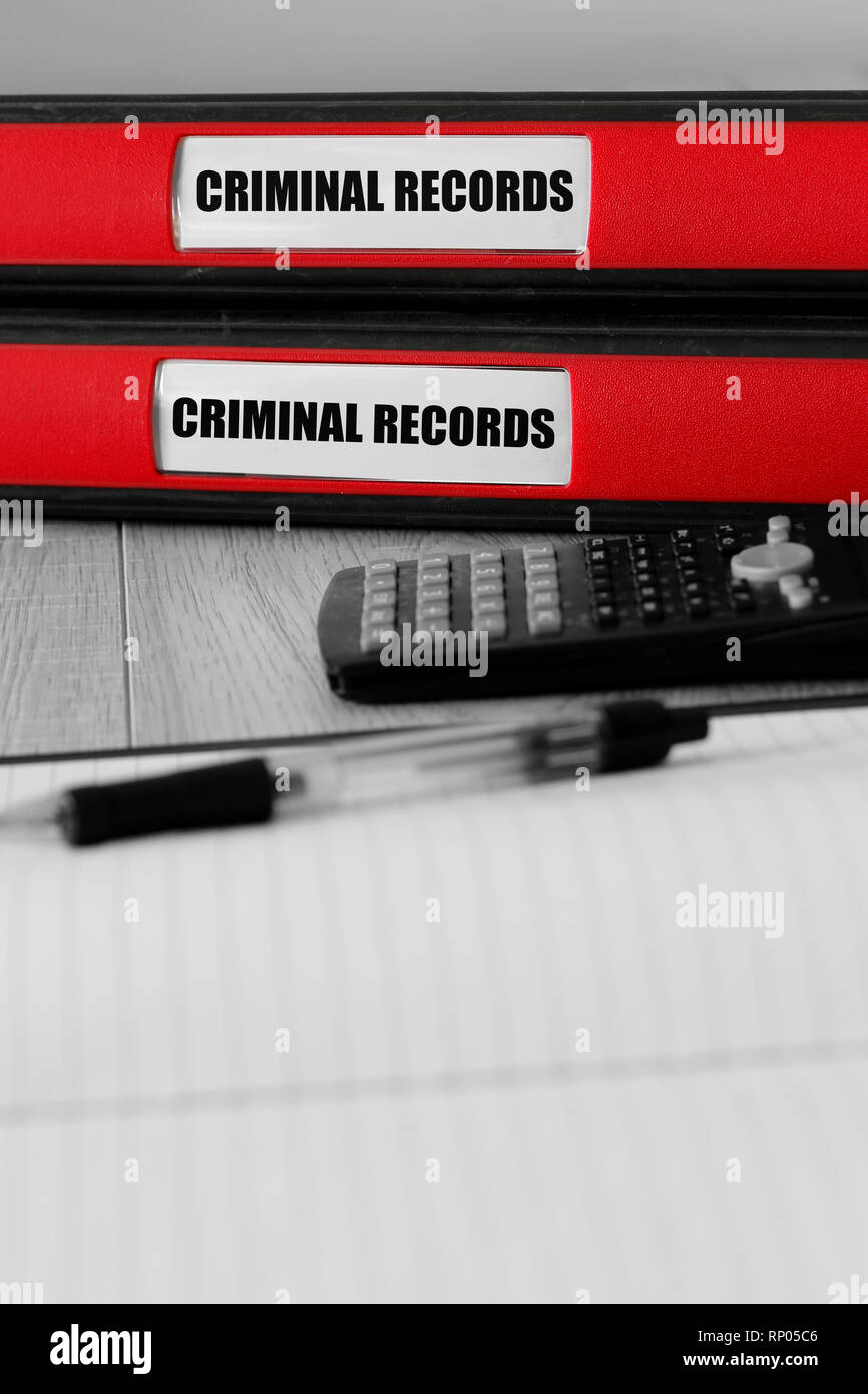 Red folders with criminal records written on the label on a desk with ...