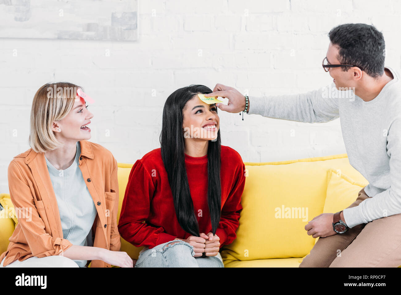multicultural friends having fun while fixing stickers on foreheads ...