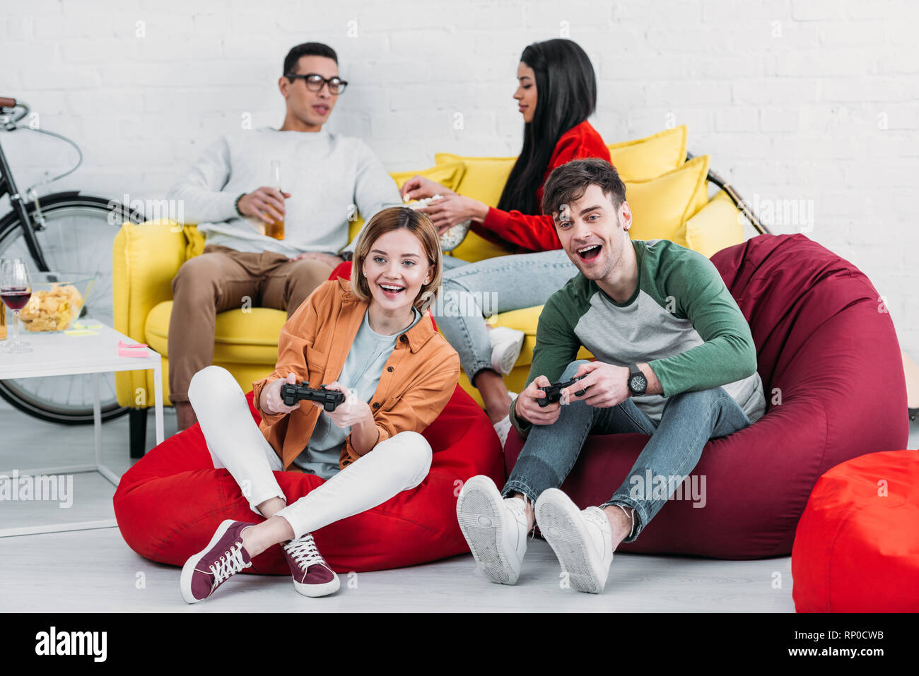 happy multicultural friends playing video game and enjoying drinks and ...