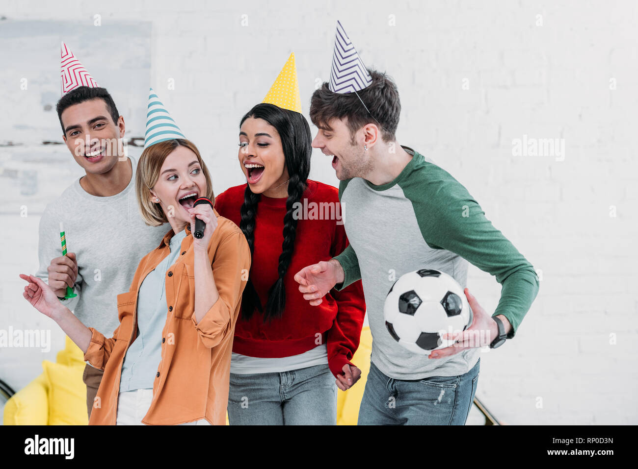 cheerful multiethnic friends in multicolored paper hats having fun at ...