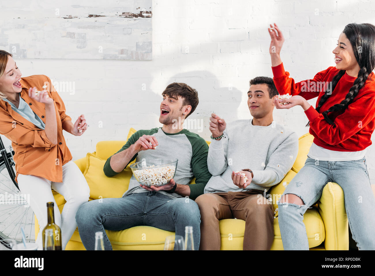 multicultural friends fooling around while throwing popcorn at each ...
