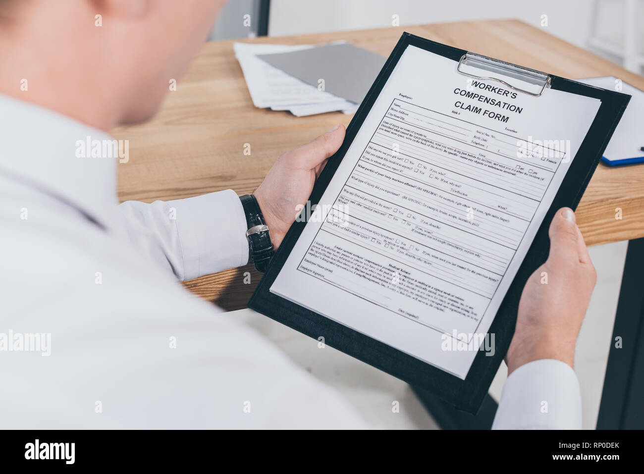 cropped view of adult businessman reading compensation claim form at ...