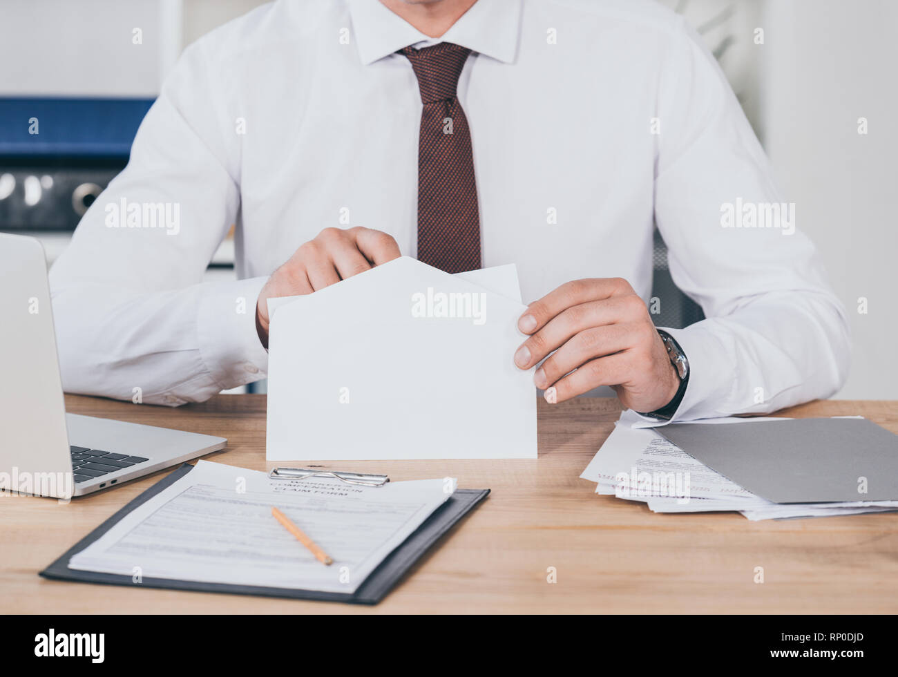 cropped view of businessman opening envelope in office, compensation ...