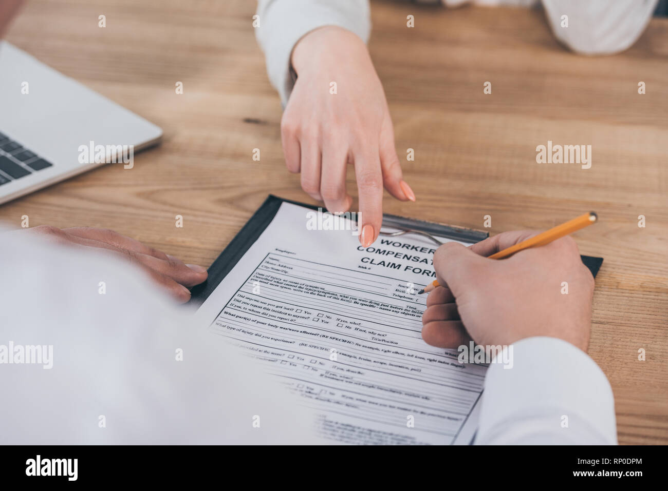 cropped view of businessman filling in compensation claim form at ...