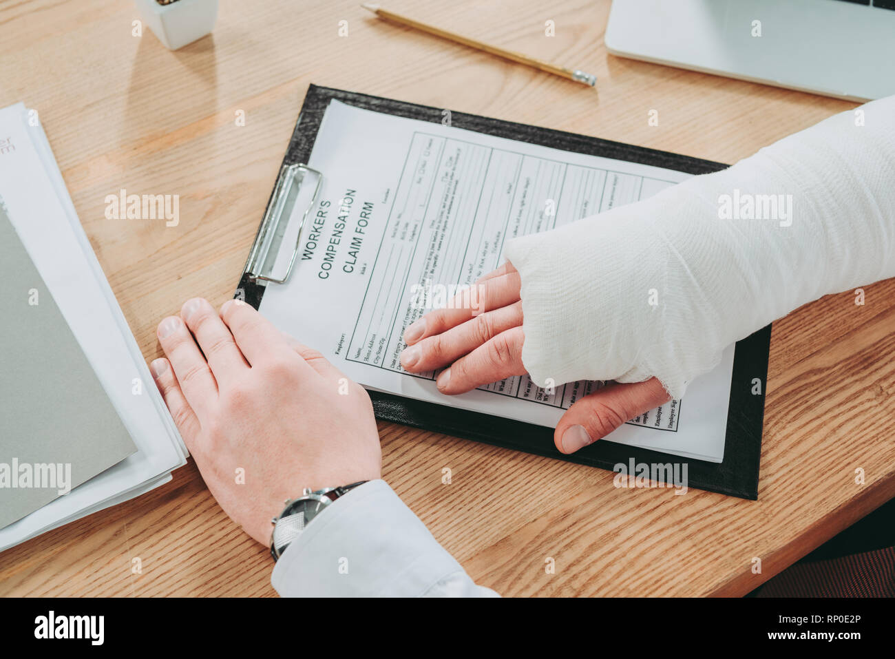 cropped view of worker with broken arm in gypsum holding hands on ...