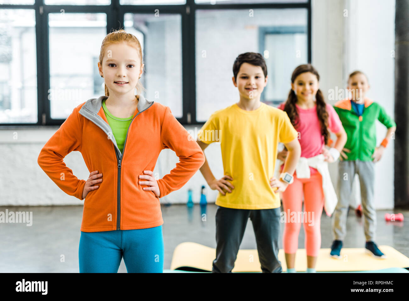 Group of kids standing in gym with arms akimbo Stock Photo - Alamy