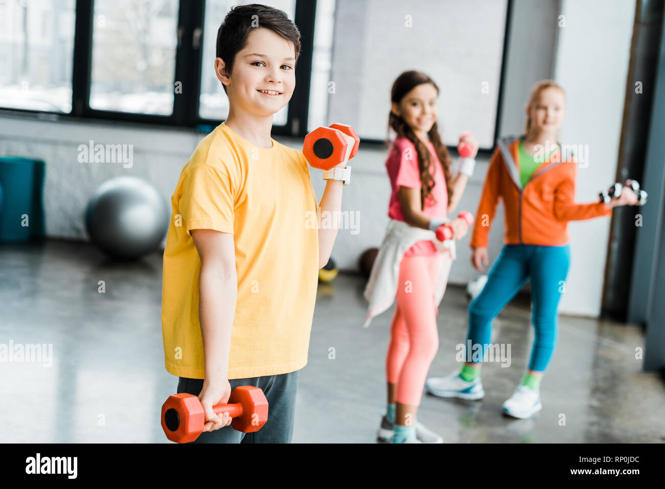 Group of kids training with dumbbells in gym Stock Photo - Alamy